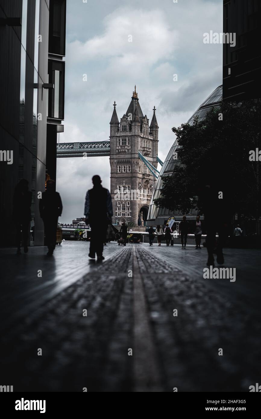 A vertical shot of the Tower Bridge under a cloudy sky in London ...