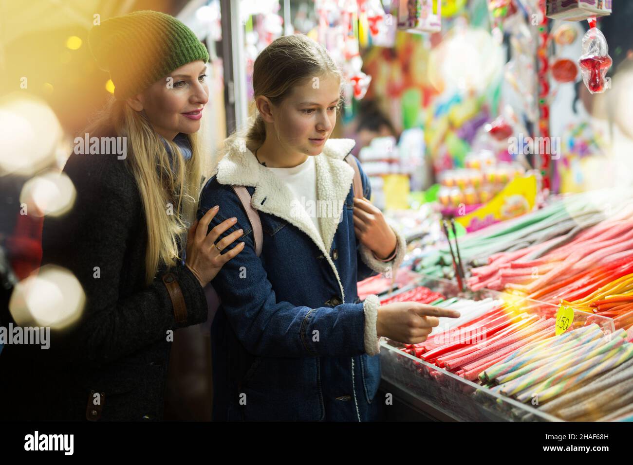 Mother and daughter standing at outdoor sweet shop and choosing candies ...