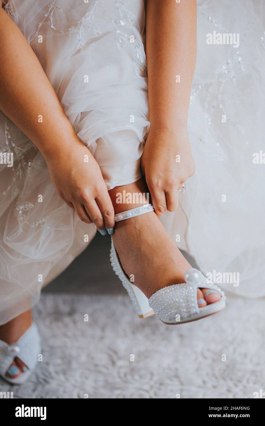 The bride putting on her white shoes and getting prepared for her ...