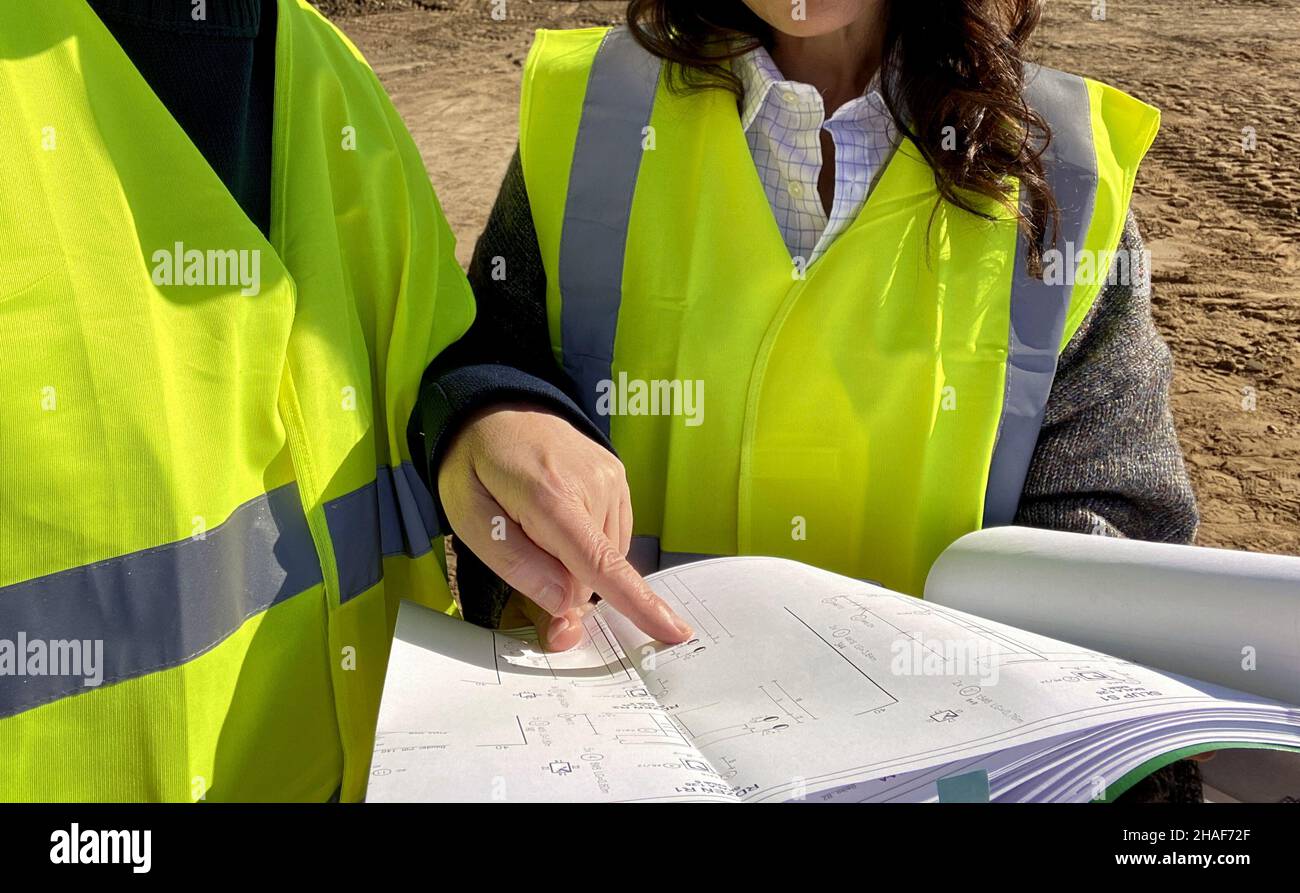 Two constructors holding a building plan at the construction site Stock ...