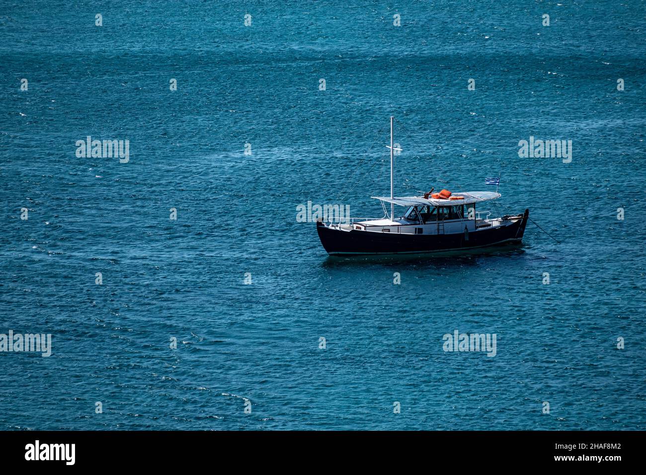 A lonely boat floating in the open blue sea; a view from Crete island ...