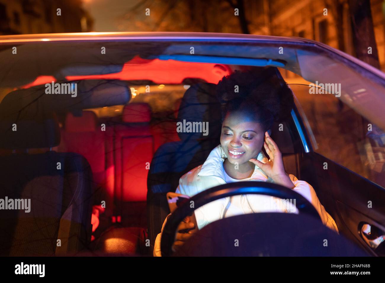 Happy african woman driver using mobile, afro female chatting online in ...