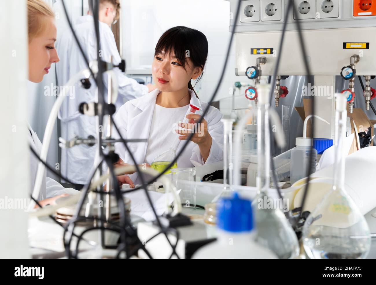 Intelligent yuong Chinese girl working with reagents in test tubes ...