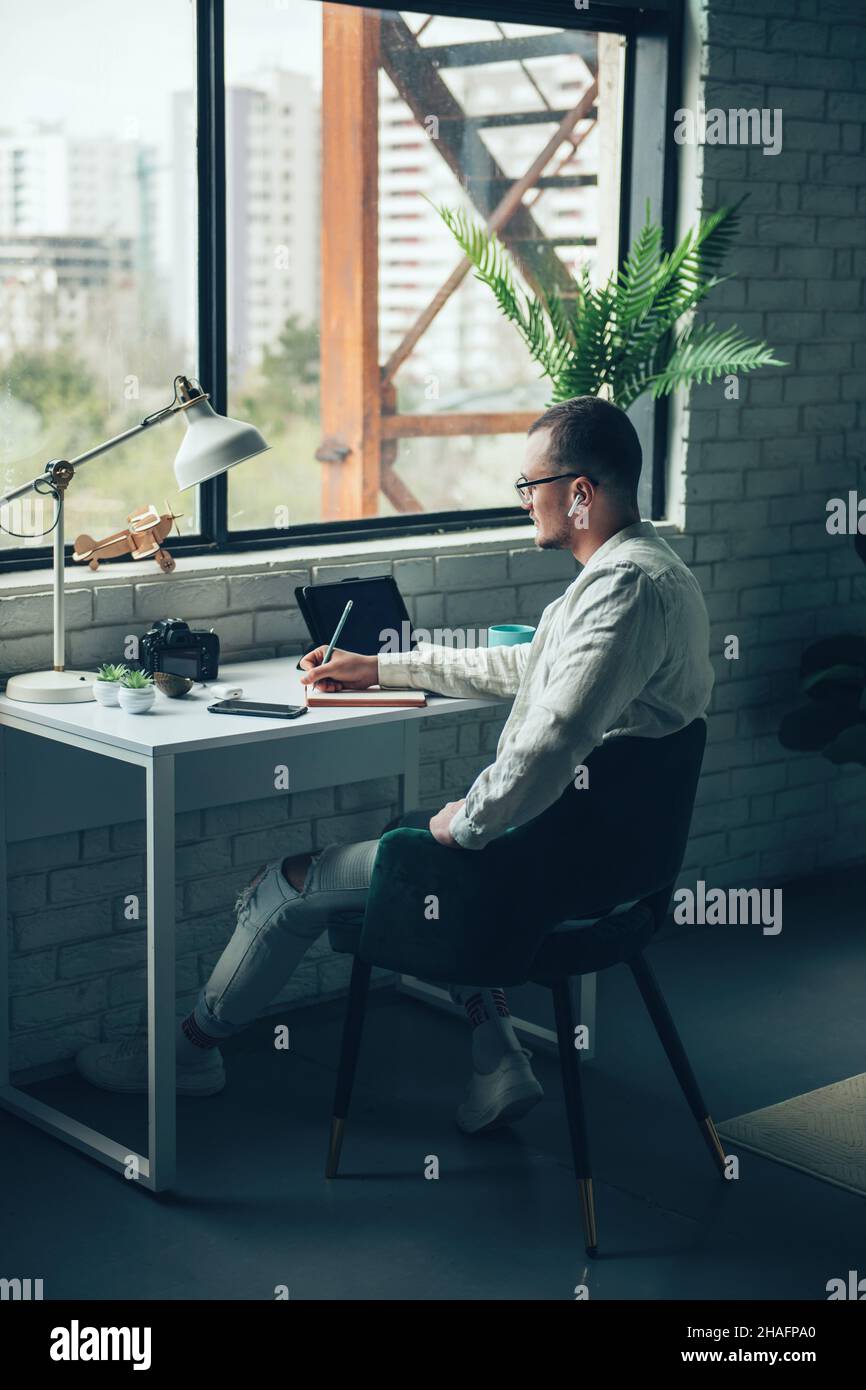 Back view of an caucasian man noting schedule on diary at business ...