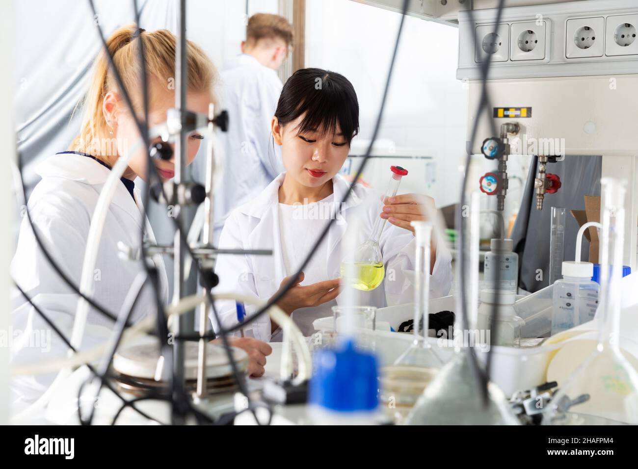 portrait of intelligent young Chinese girl working with reagents in ...