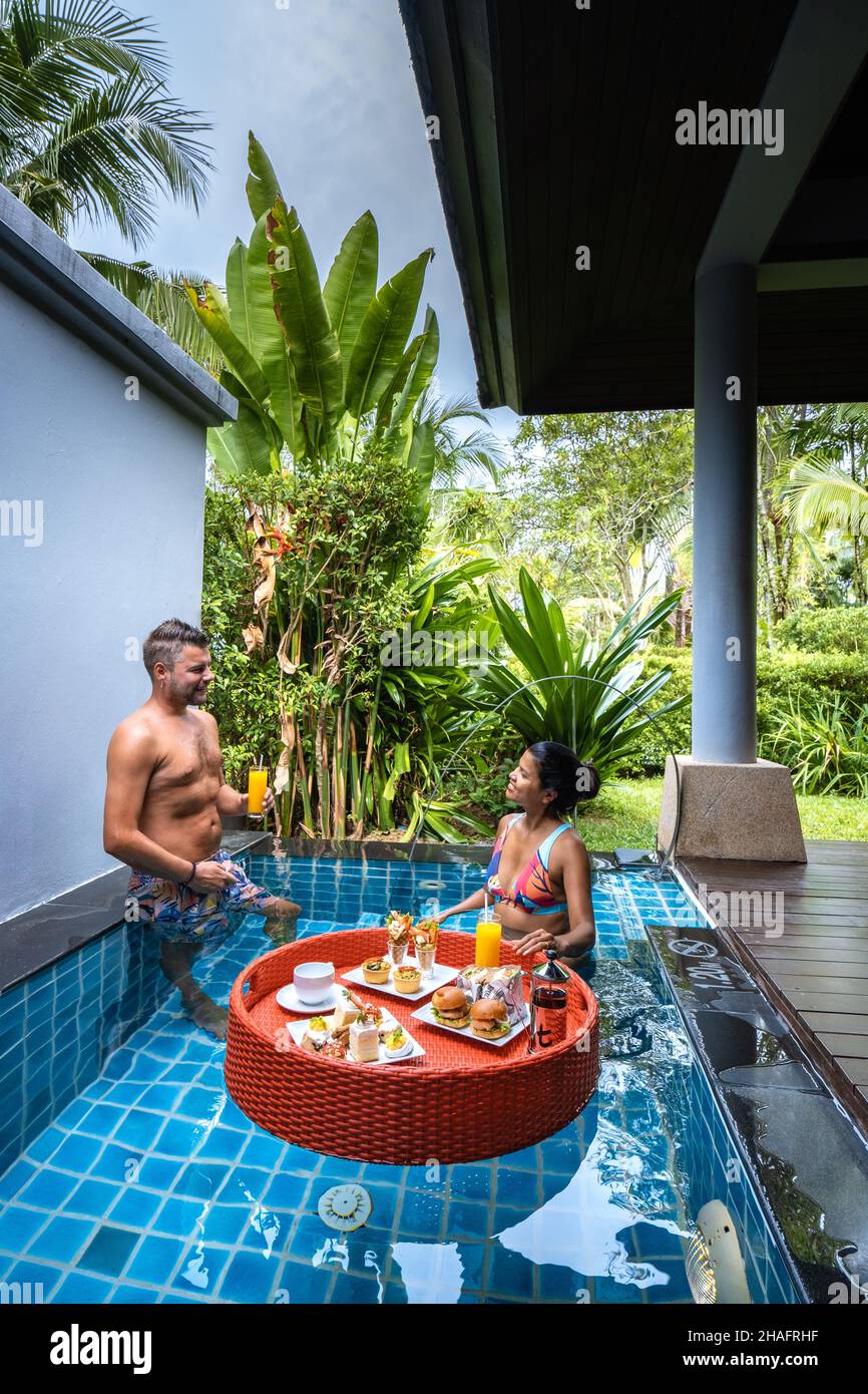 couple man and woman having floating breakfast High tea in poool in ...