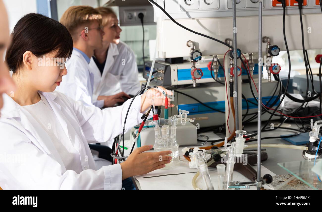 Multiracial team of young scientists performing experiments on lab ...