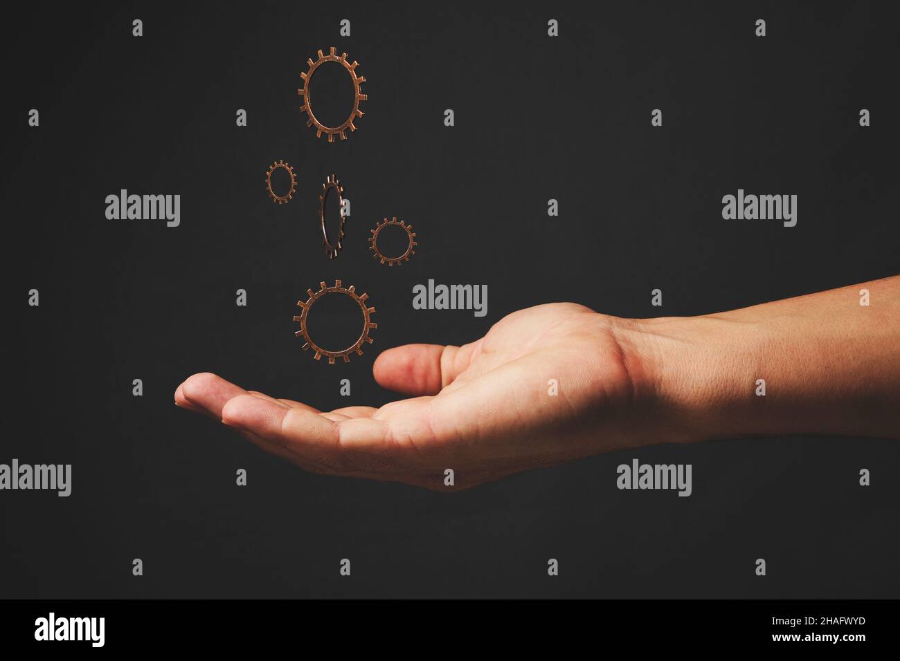 Hand and levitating gears on a gray background. Concept progress ...