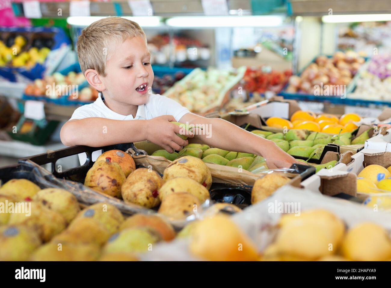 Portrait of happy cheerful smiling little boy choosing fruits at store ...