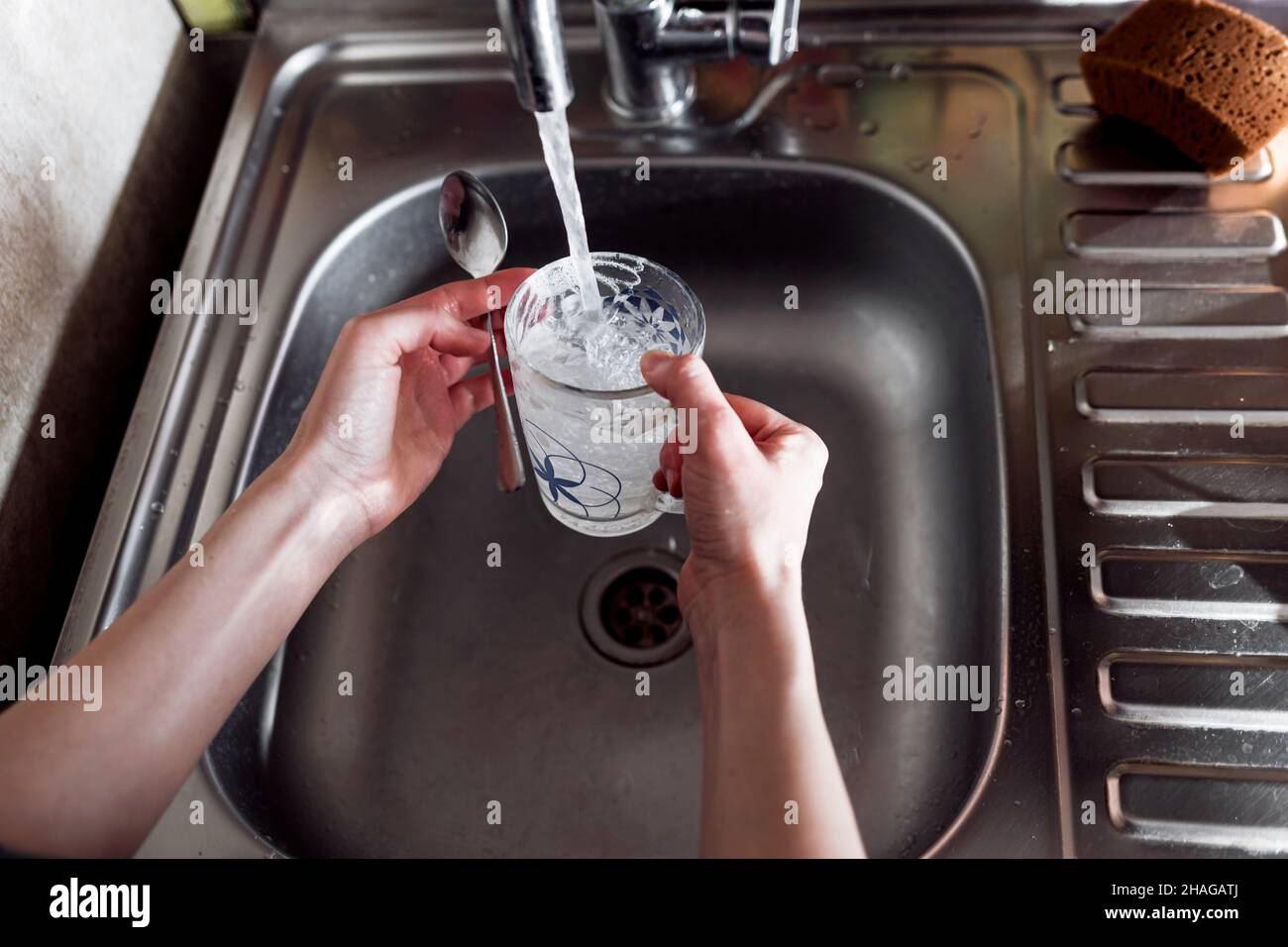 Human hand washing dish or pouring glass with fresh drink water at ...