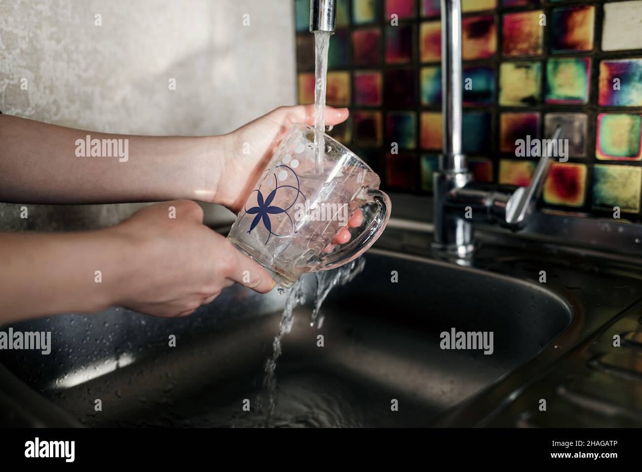 close-up of women's hands washing a mug under a stream of water ...
