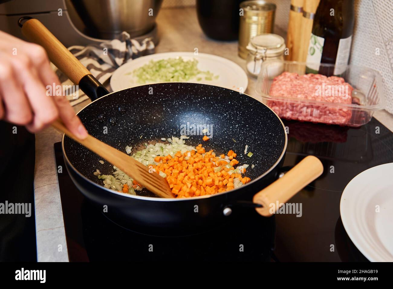 Woman cooking bolognese sauce in pan on induction stove in the kitchen ...