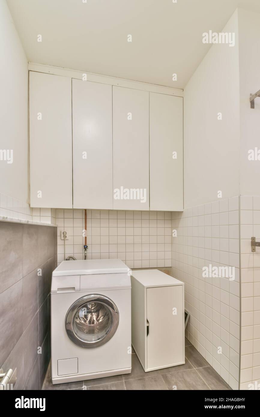 Laundry room with washing machine and closets above it Stock Photo - Alamy