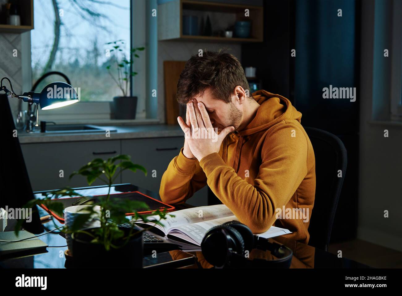 Thirty years old tired man working late remotely at home office, using ...
