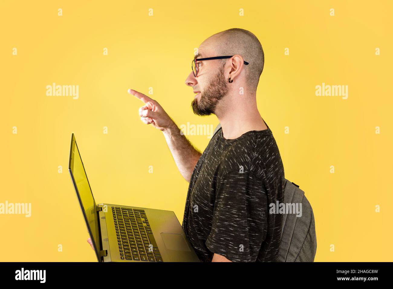 Using a laptop. A bald, bearded man with glasses is holding a laptop ...