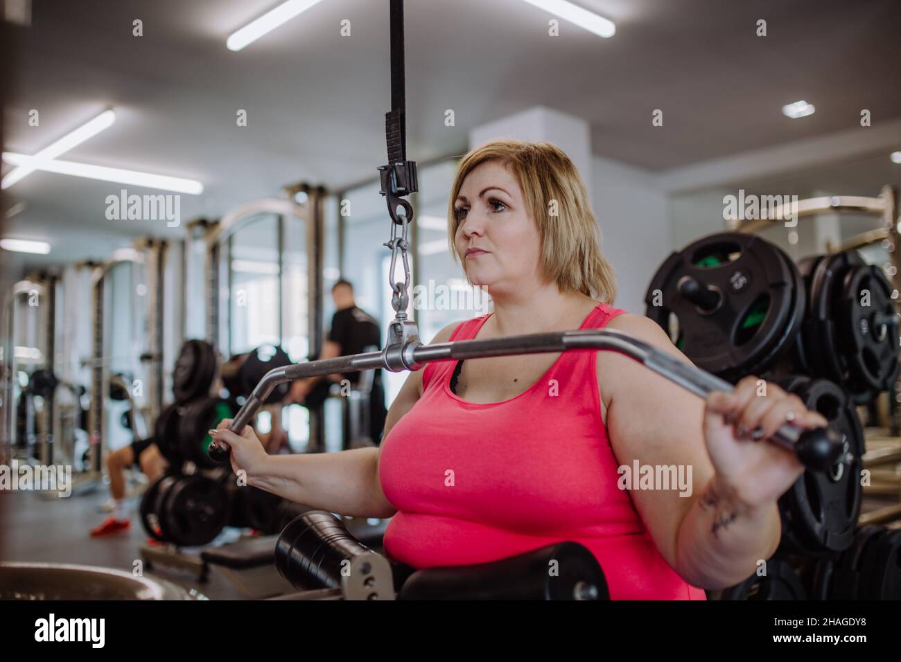 Mid adult plus size woman working out on a lat pulldown machine indoors ...