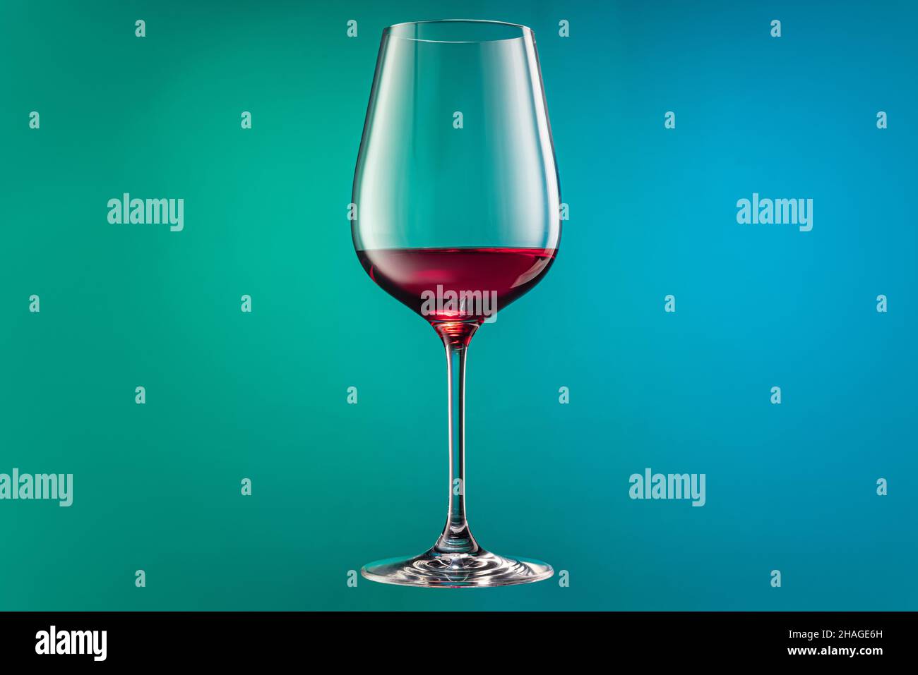 Close-up red wine glass isolated over gradient blue and green color ...