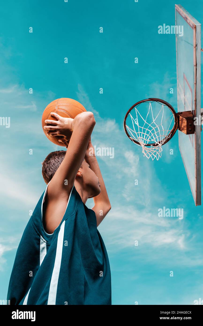 Sports and basketball. A young teenager in a blue tracksuit throws a ...