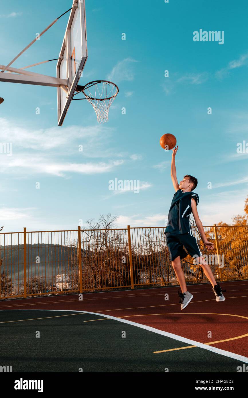 Sports and basketball. A young teenager in a blue tracksuit throws a ...
