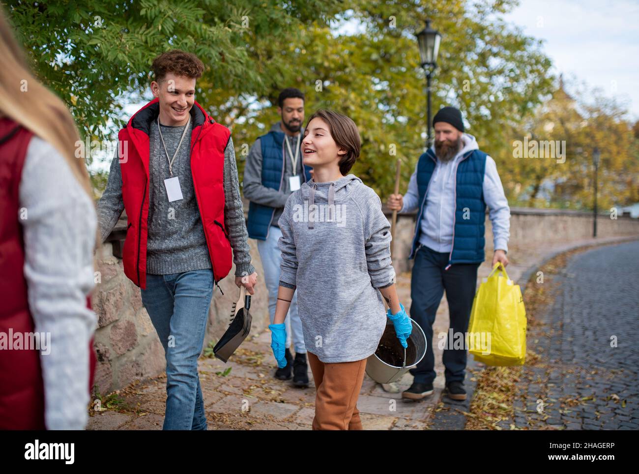 Diverse group of happy volunteers walking with tools to do street clean ...