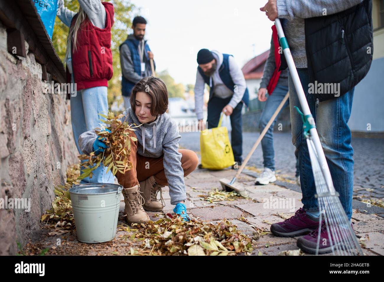 Diverse group of happy volunteers cleaning up street, community service ...
