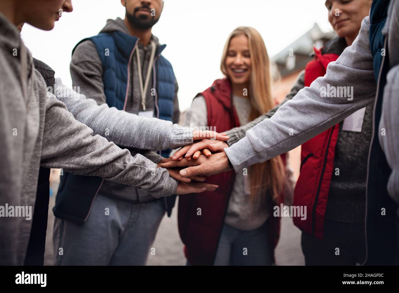 Close up of group of happy community service volunteers stacking hands ...