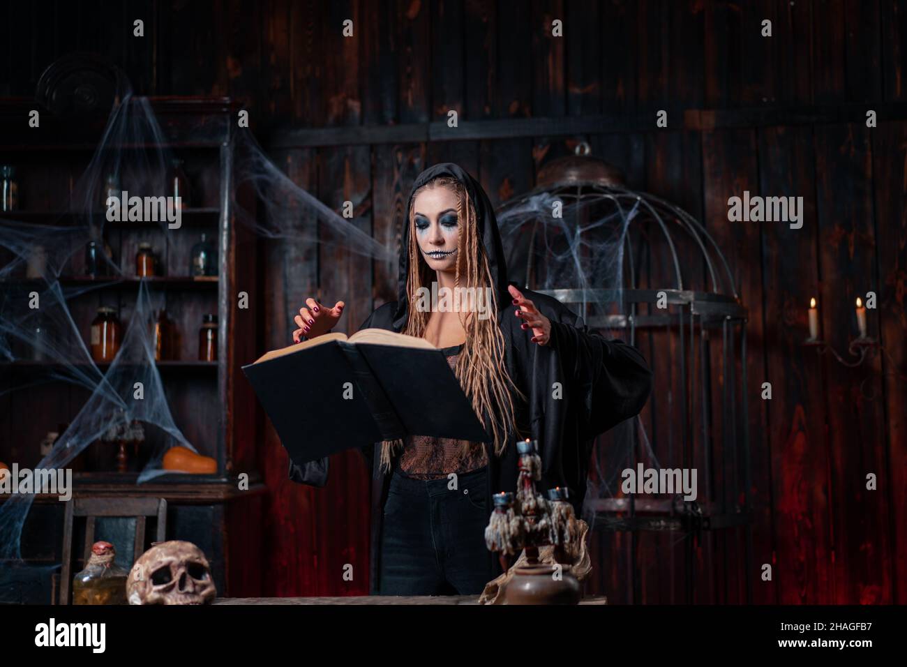 Halloween concept. Witch dressed black hood standing dark dungeon room ...