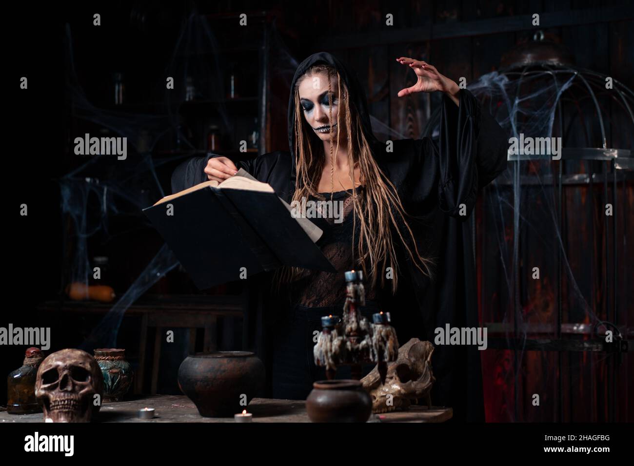 Halloween concept. Witch dressed black hood standing dark dungeon room ...