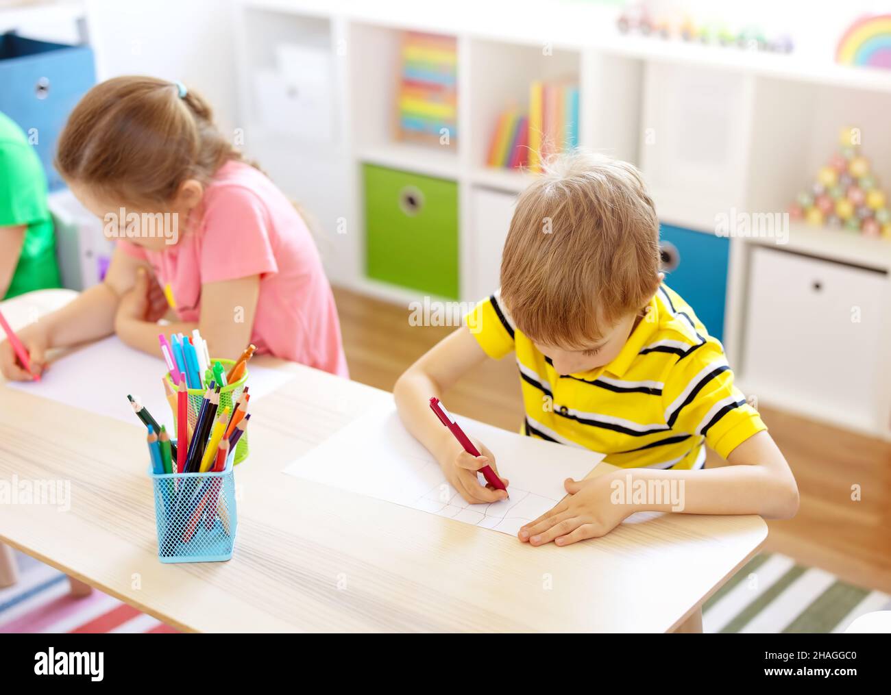 Schoolkids in the classroom sitting at the tables and writing a lesson ...