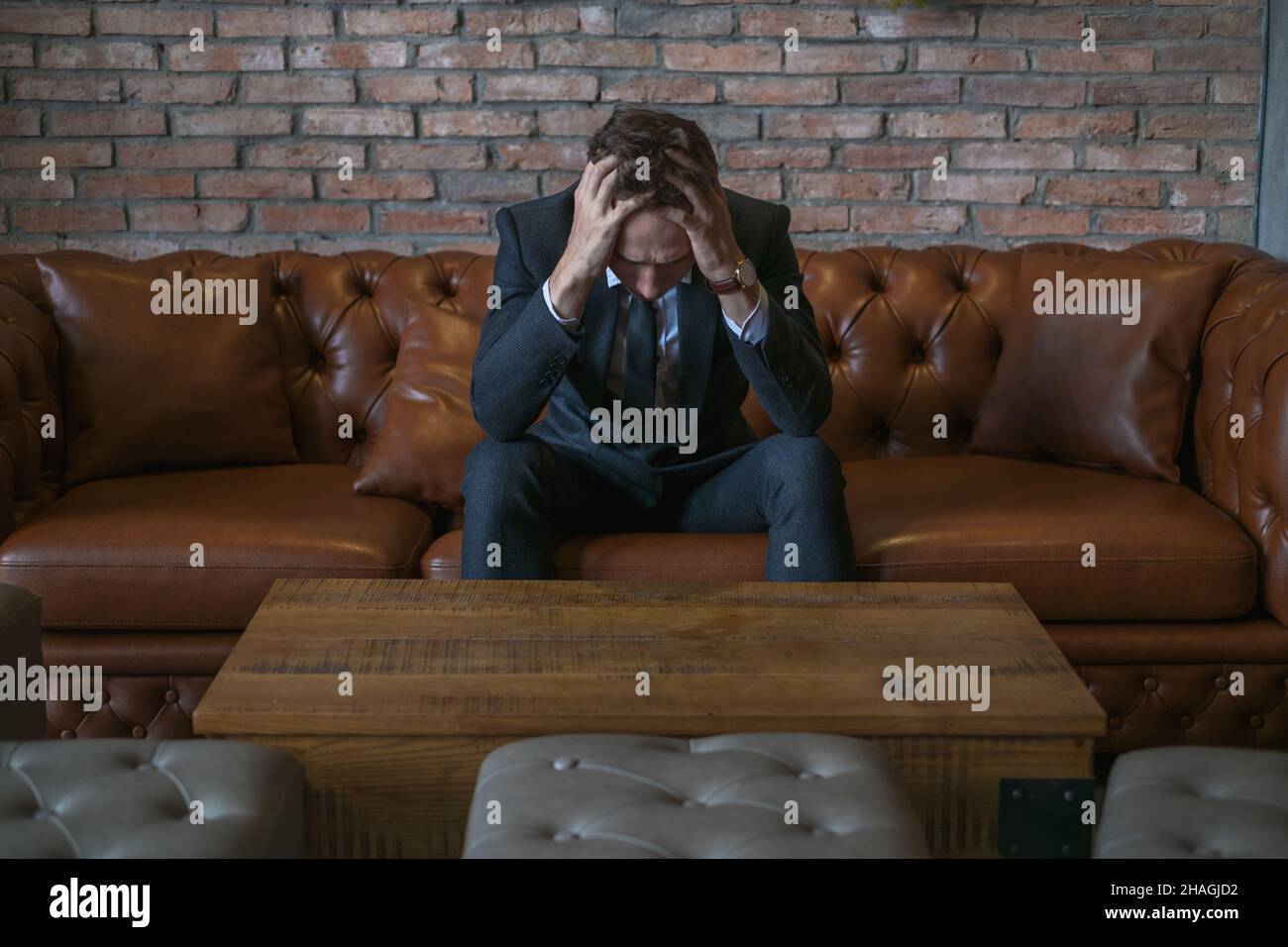 Young caucasian business man in formal suit sitting on brown leather ...
