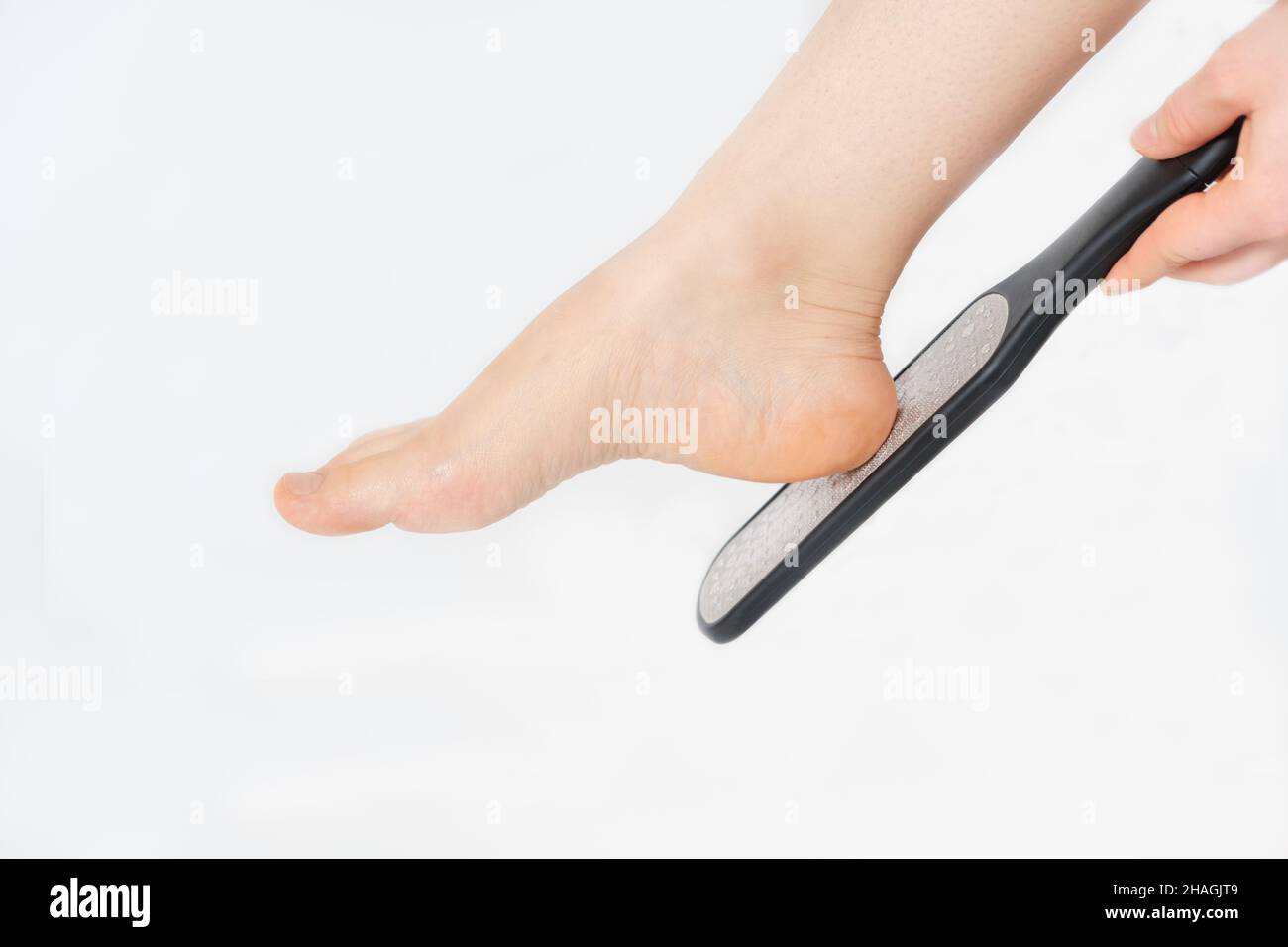 Women's foot on a white background, polishing the heel with a file ...