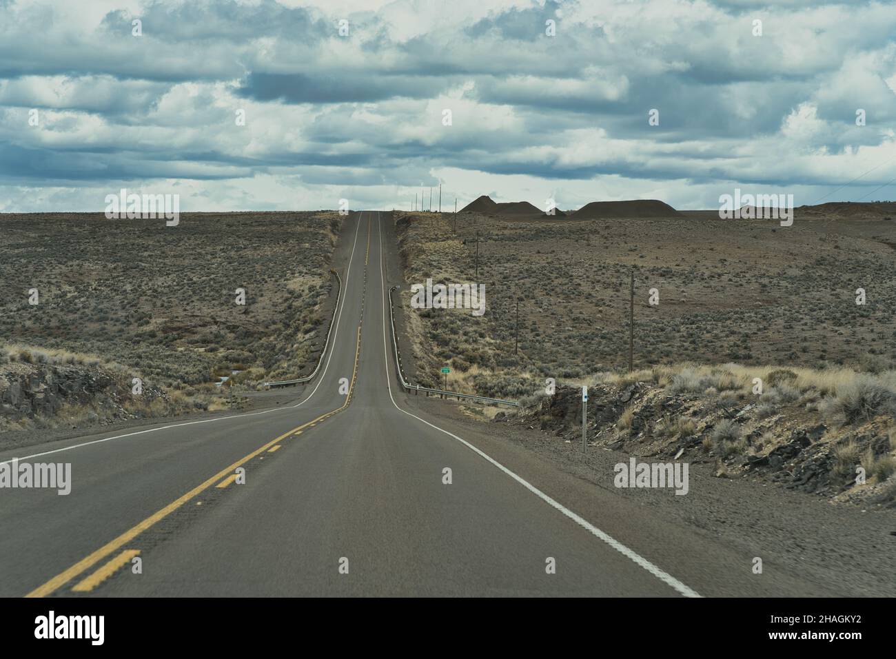 Empty U.S. 95 asphalt highway in Eastern Oregon under a blue sky with ...
