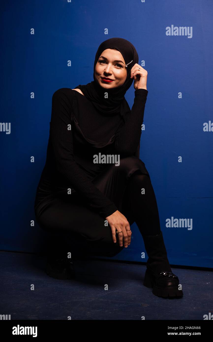 Fashion muslim model in black hijab is posing on blue background in ...