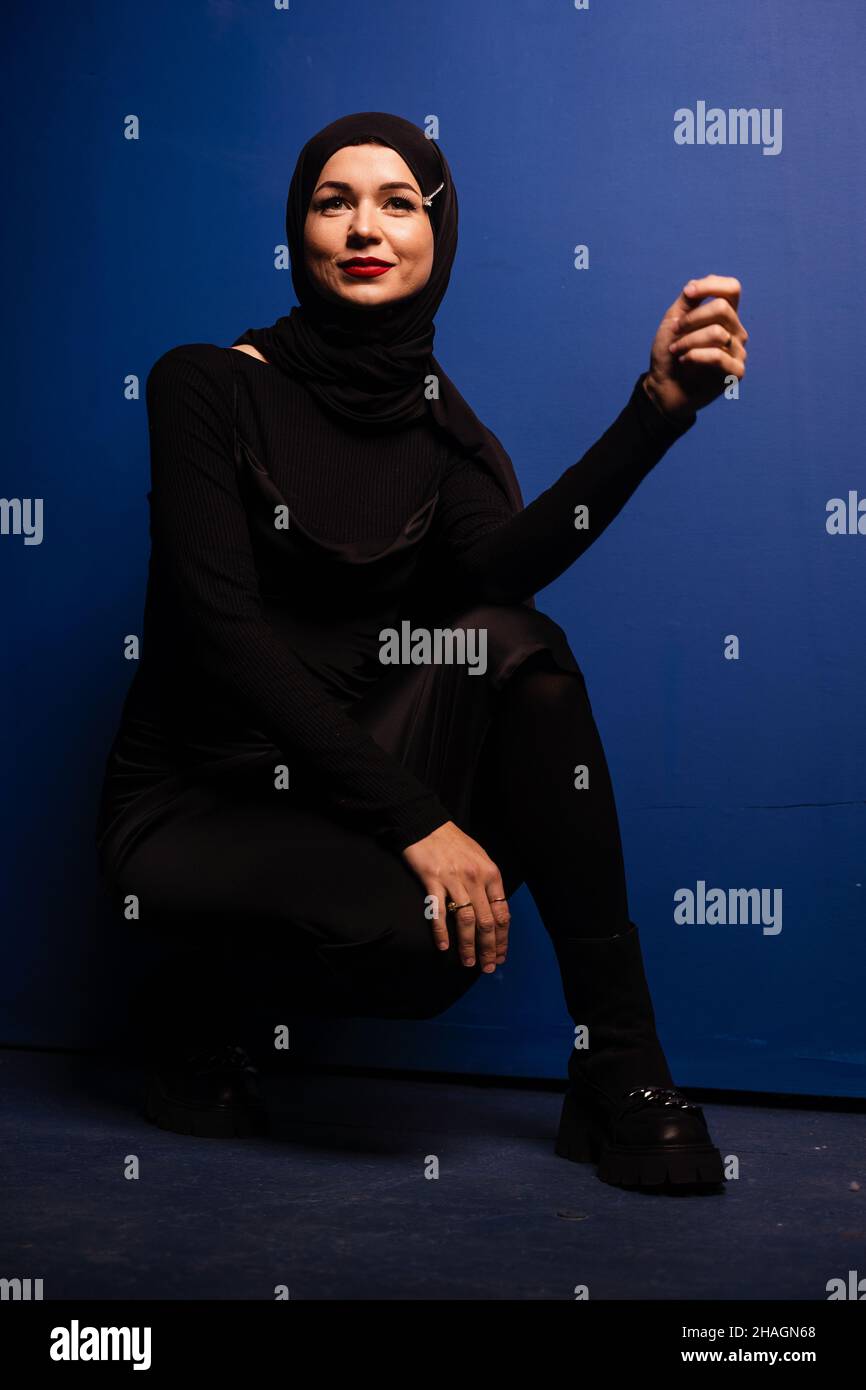 Fashion muslim model in black hijab is posing on blue background in ...