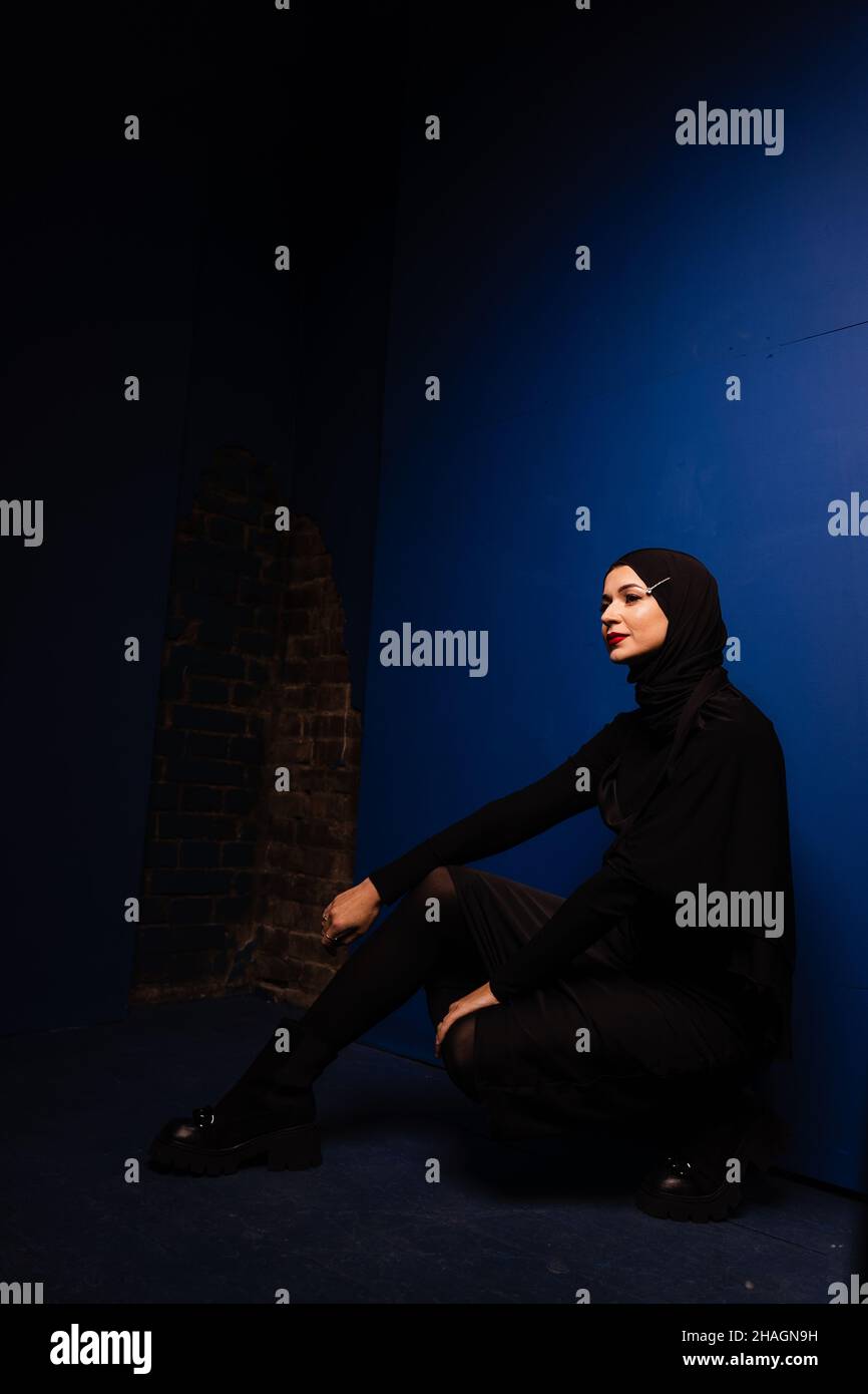 Fashion muslim model in black hijab is posing on blue background in ...