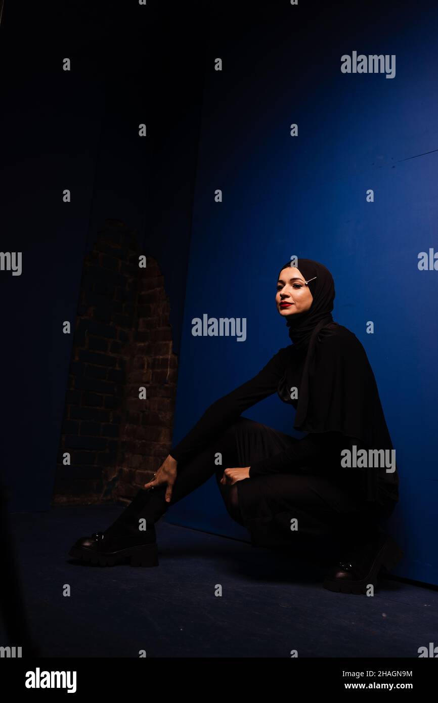 Fashion muslim model in black hijab is posing on blue background in ...