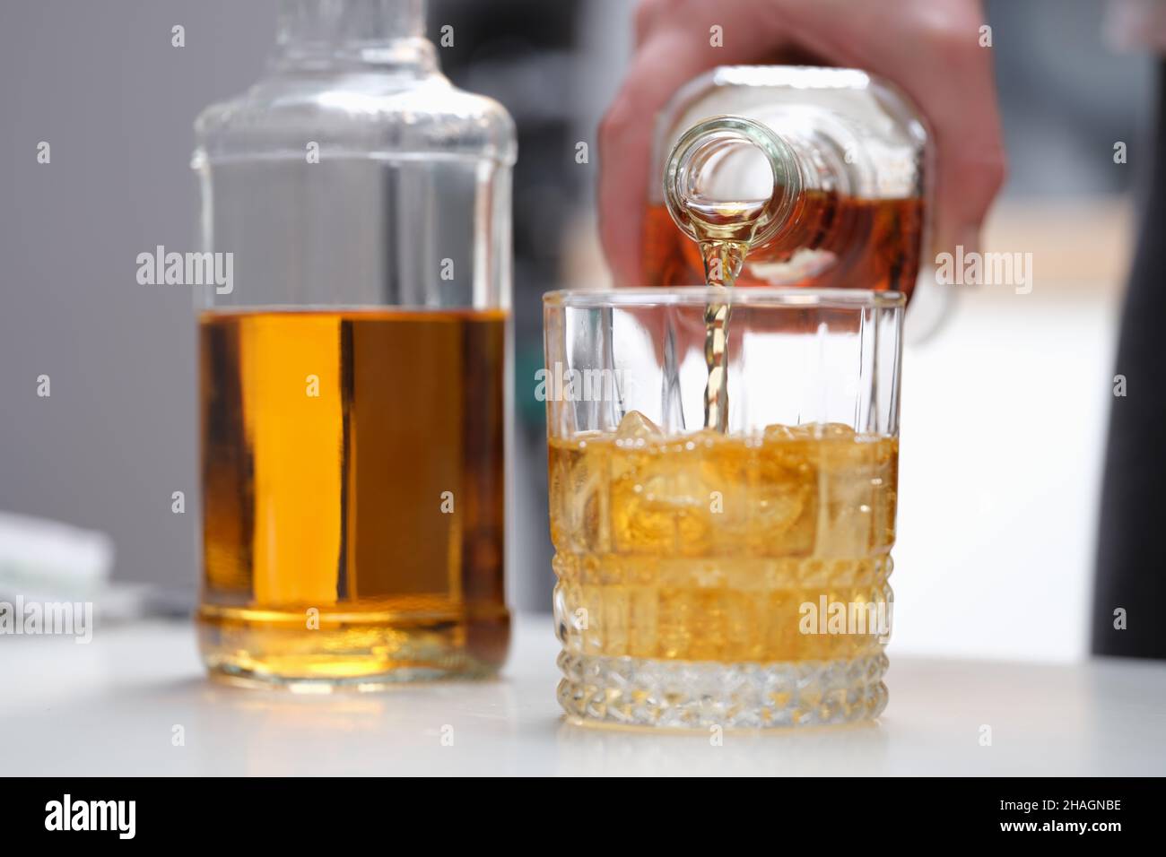 A hand pours a brown alcoholic drink into a glass Stock Photo - Alamy