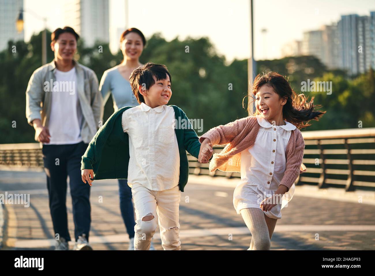 happy asian family with two children walking on pedestrian bridge in ...