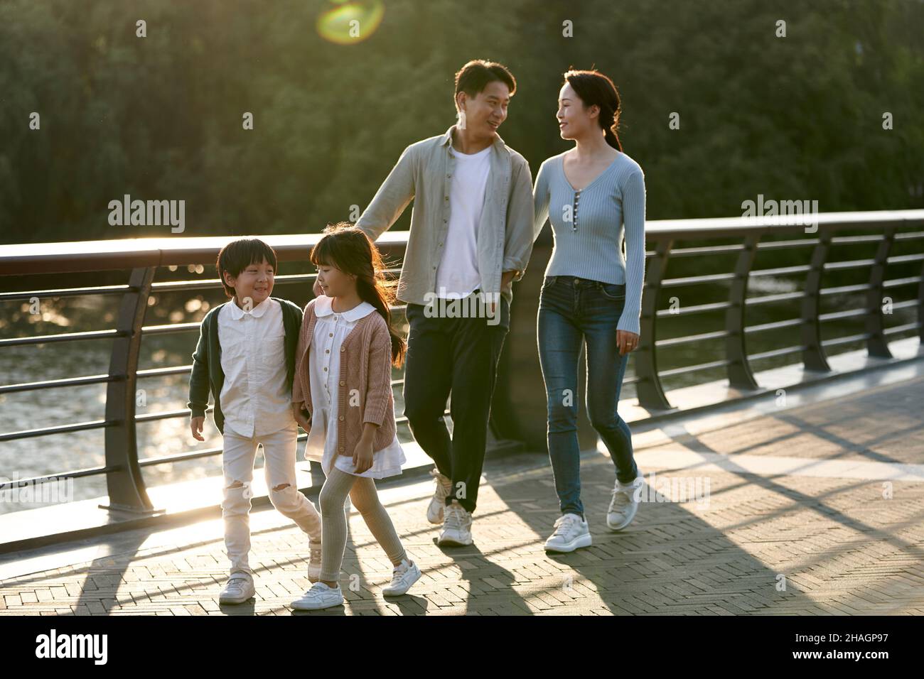 happy asian family with two children walking on pedestrian bridge in ...
