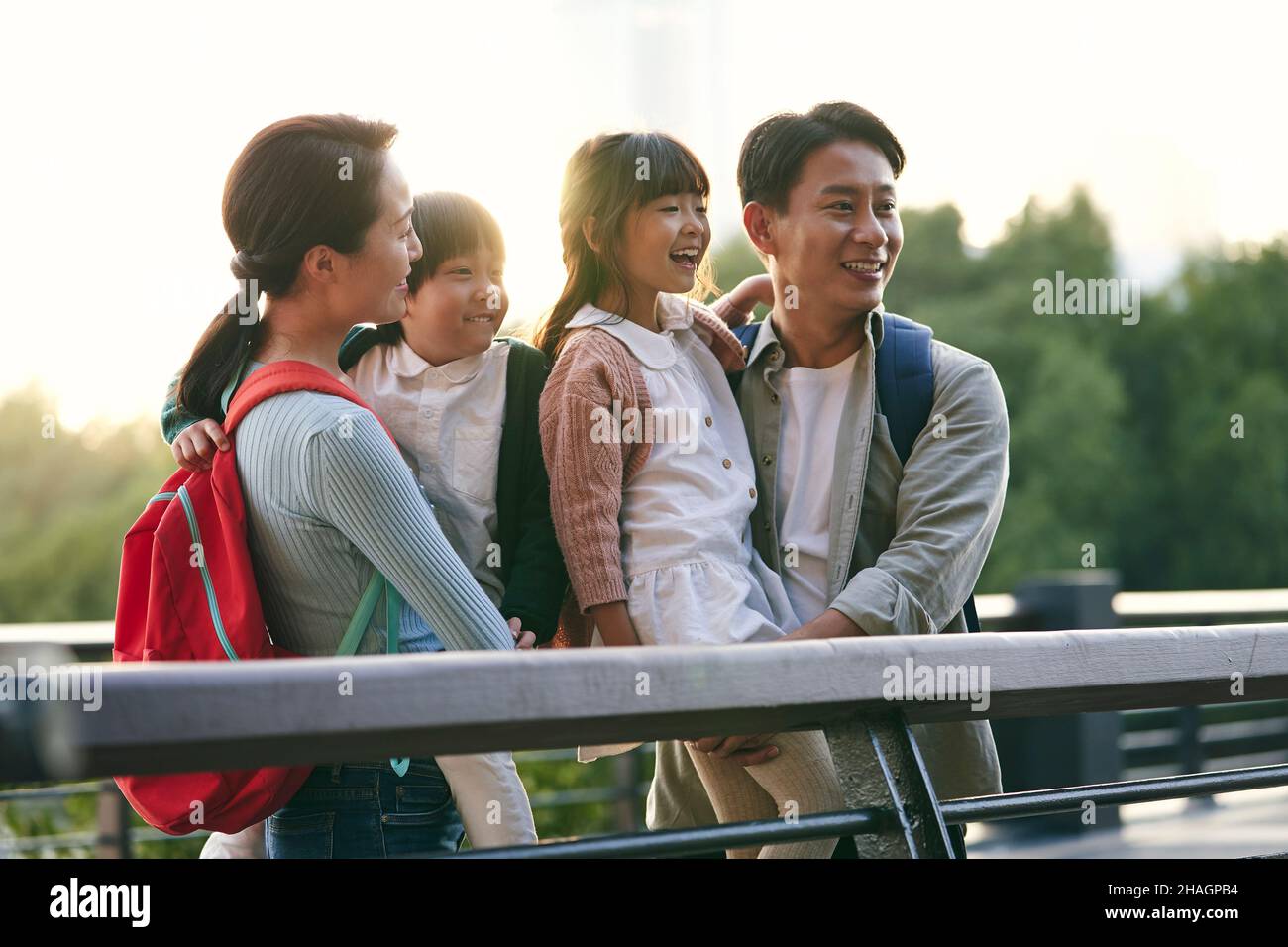 asian family with two children standing on pedestrian bridge looking at ...