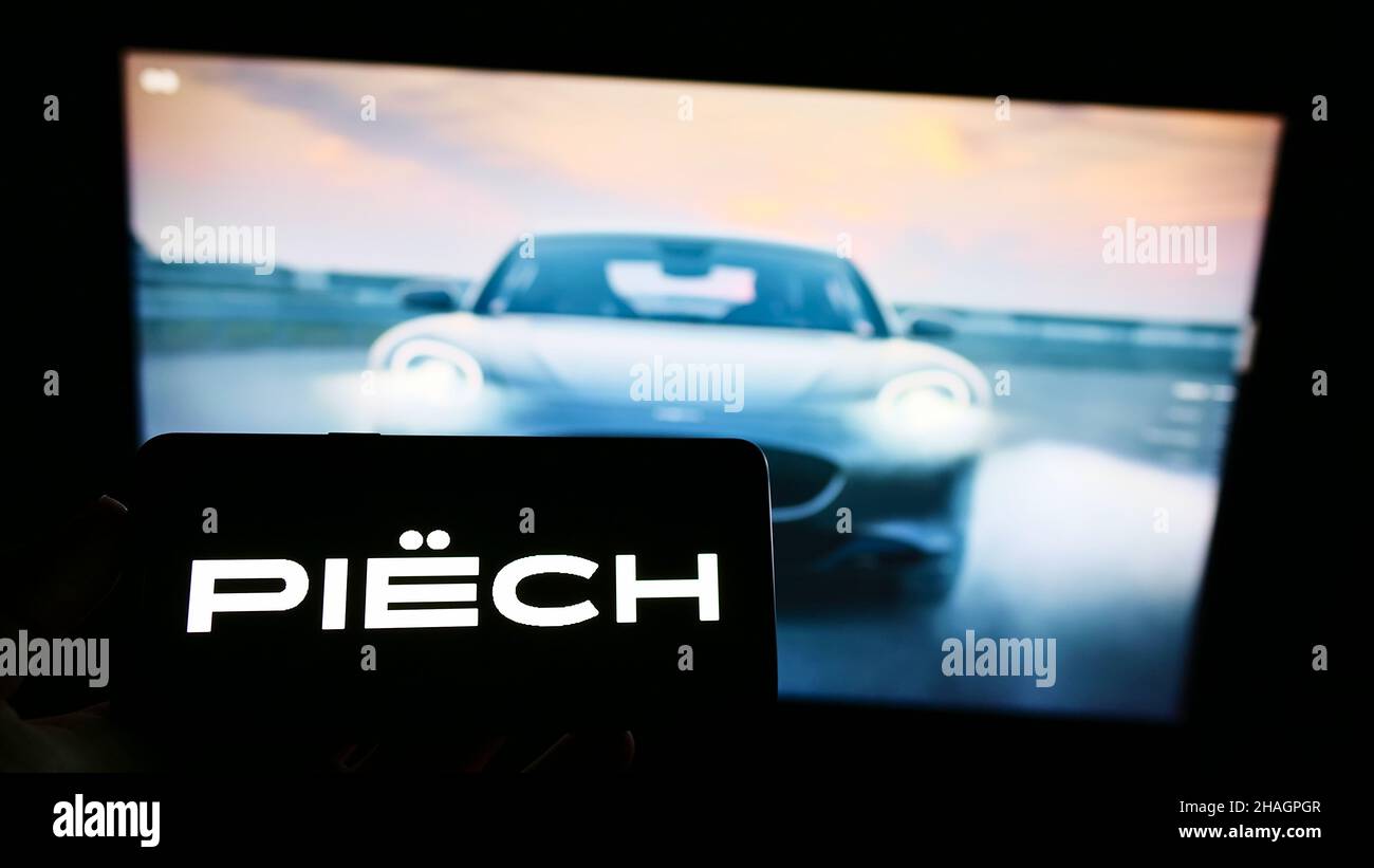 Person holding mobile phone with logo of electric car company Piech ...
