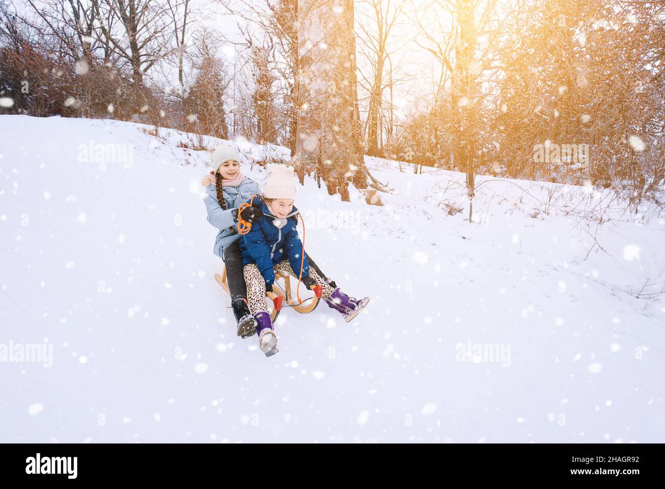 Two children ride on wooden retro sled on sunny winter day. Active ...