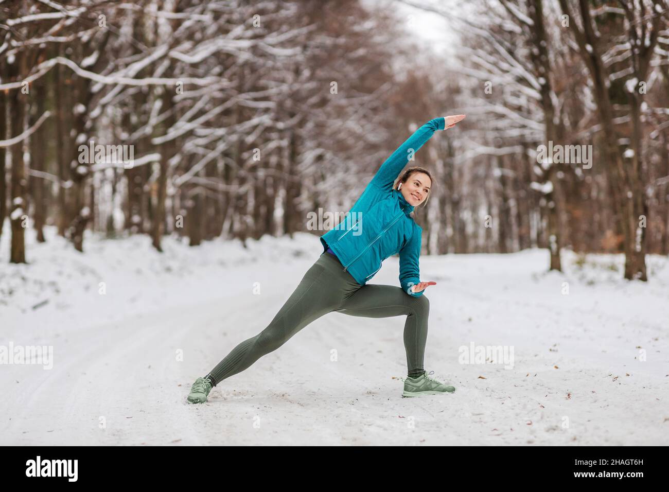 Fit sportswoman in sportswear doing yoga exercises in snowy forrest ...