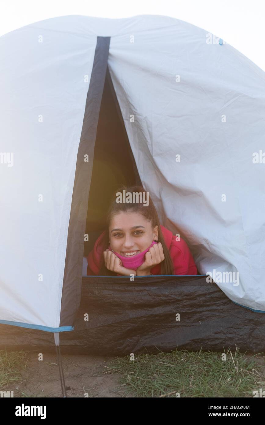 Young woman peeking out of the tent with only her head sticking out ...