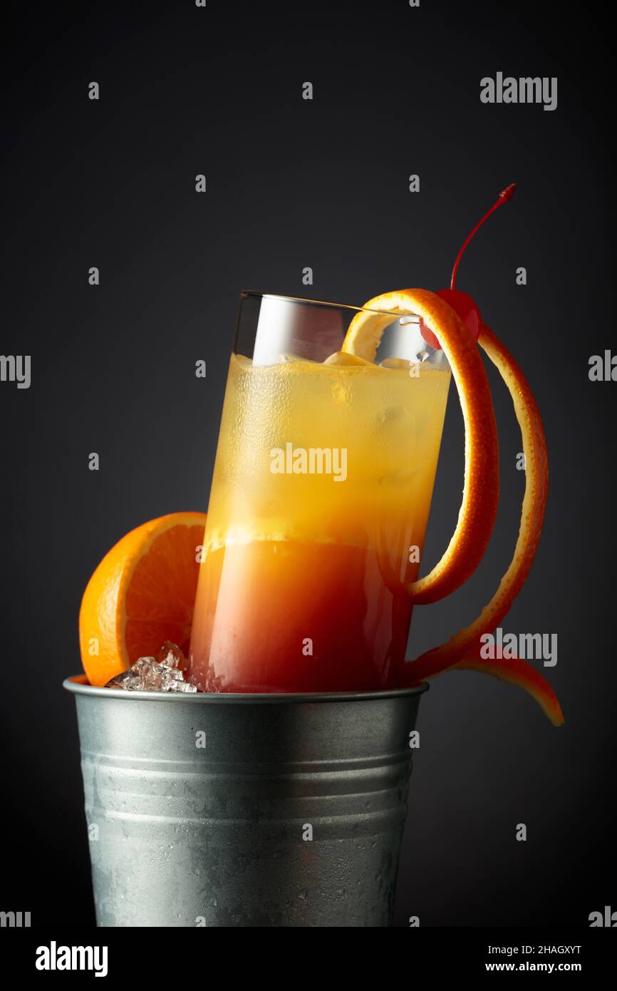 Cocktail tequila sunrise with a cherry and orange slice in a metal ...