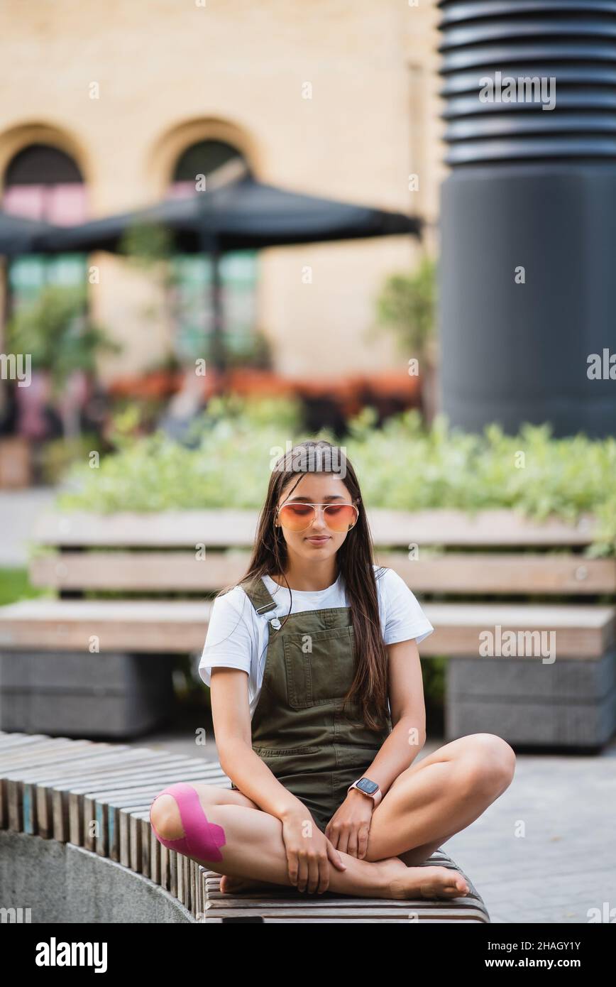 Happy young woman sitting outdoors in yoga position Stock Photo - Alamy