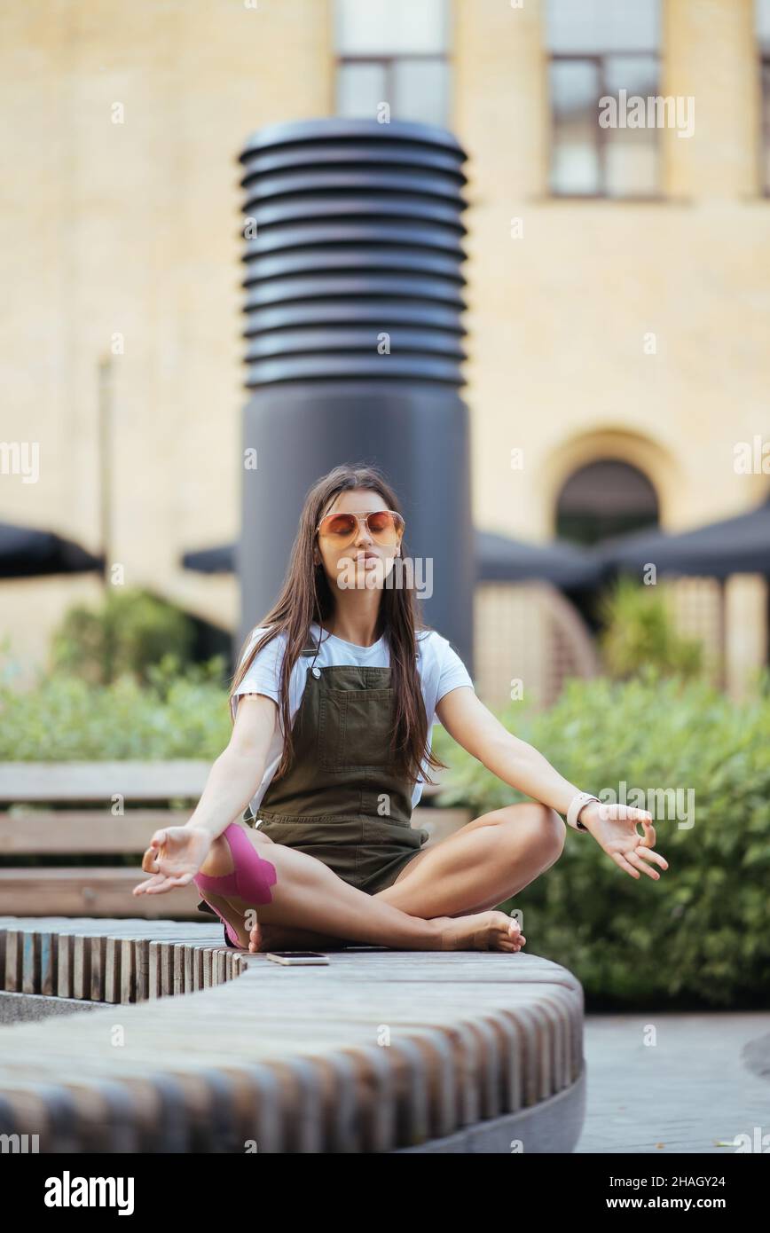 Happy young woman sitting outdoors in yoga position Stock Photo - Alamy