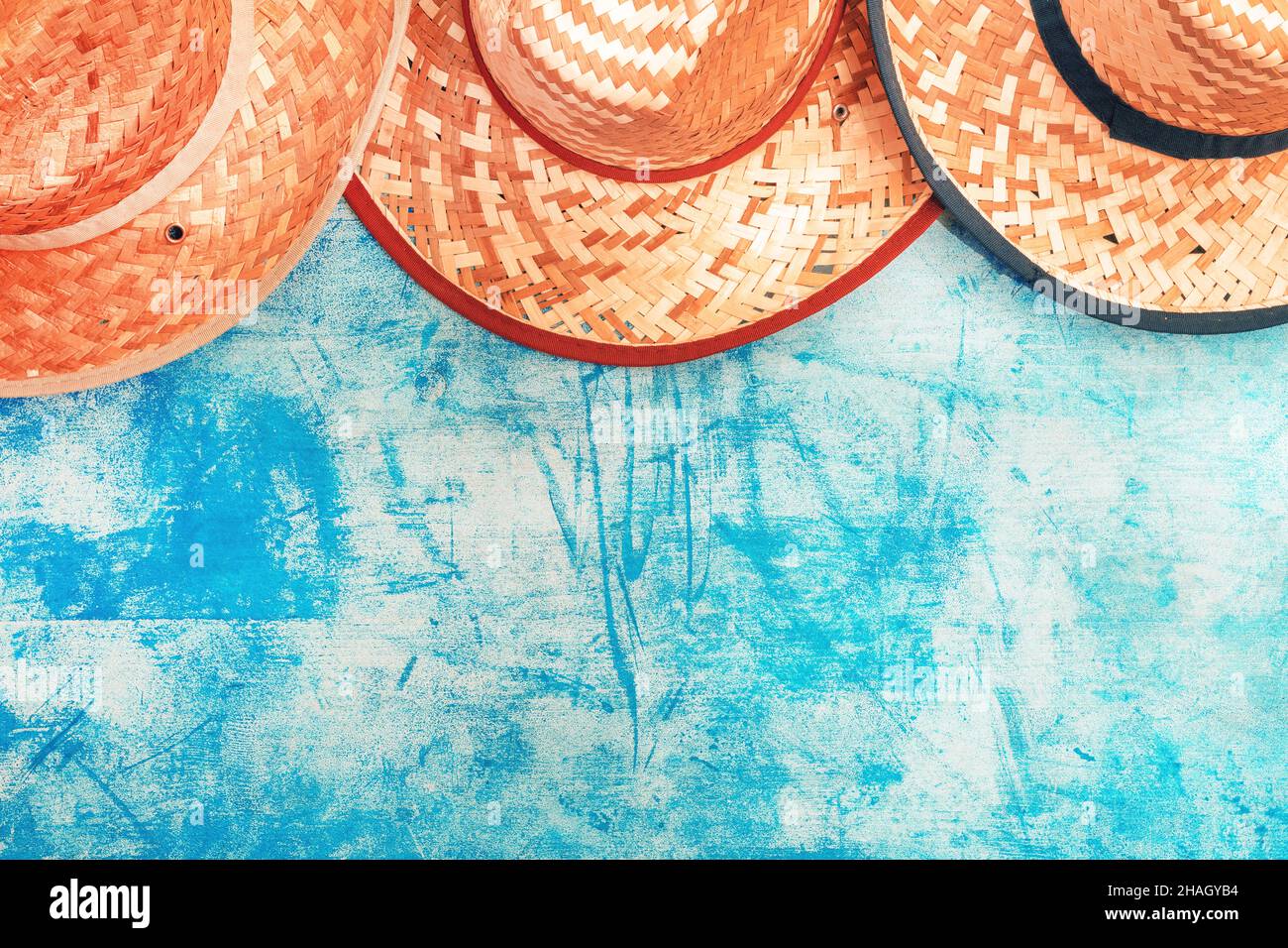Top view of three beach straw hats from above on grunge blue background ...