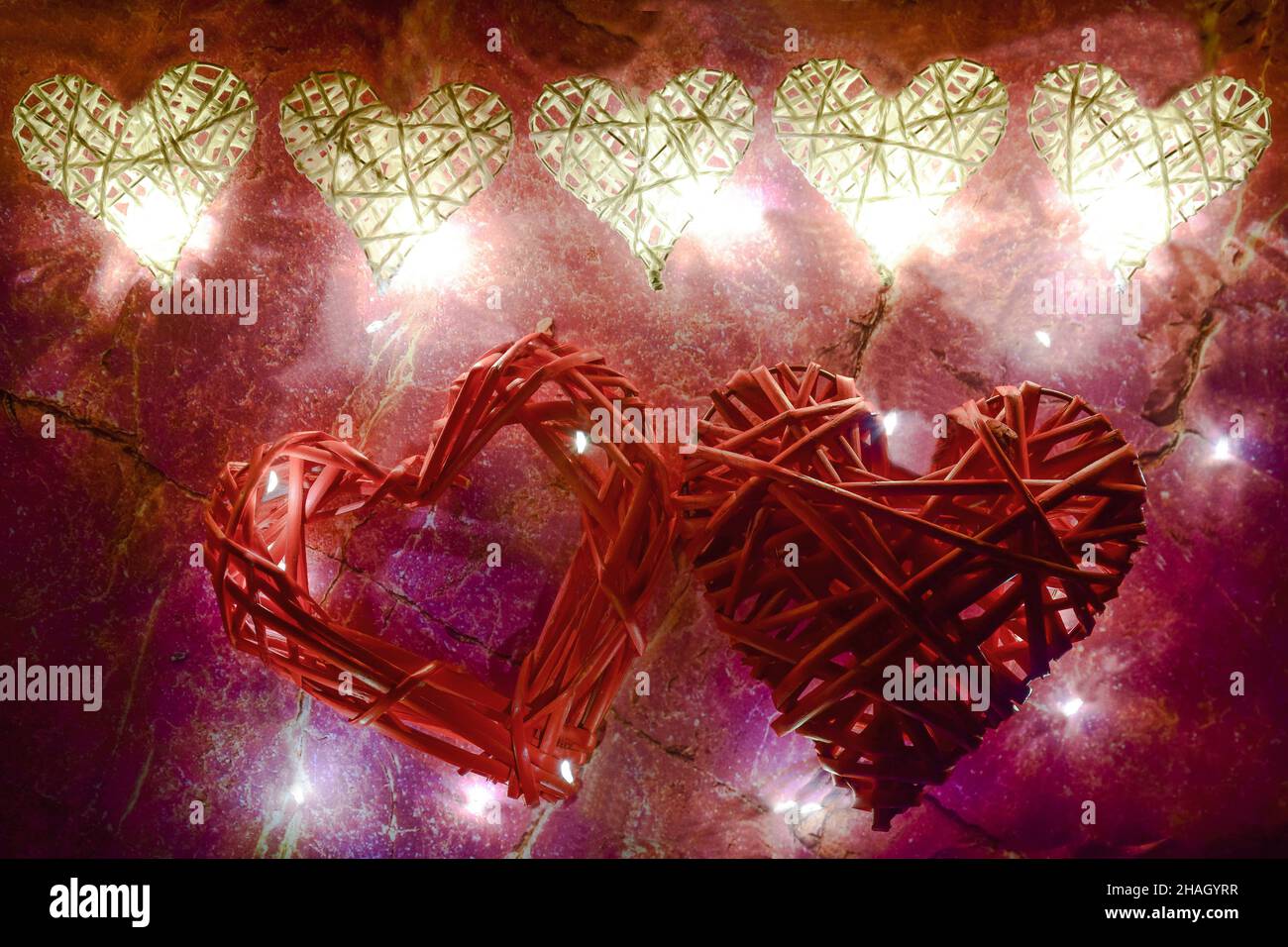 Five handmade wicker hearts with bulbs hang in a row on the marble wall ...