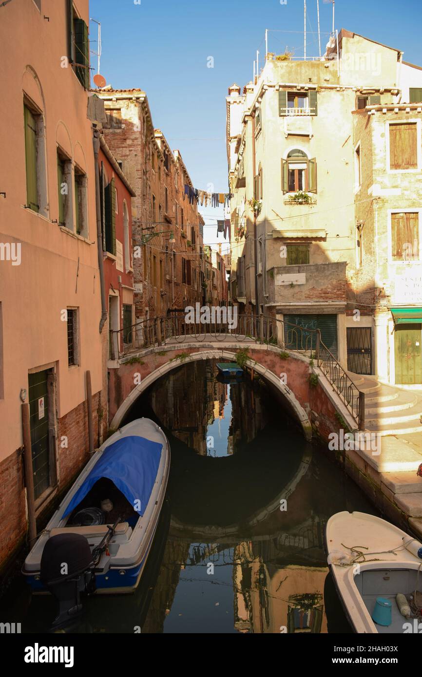 Canal in Italian Venice between ancient buildings with boats on it. And ...